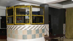 Um quarto com parede revestida de azulejos, uma mesa de jantar com cadeiras e uma cortina preta.