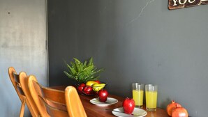 Uma mesa de jantar com pratos de fruta, copos de suco e uma tigela de bananas e maçãs.