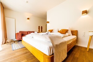 Quarto moderno com cama de madeira, sofá vermelho e tapete pequeno.