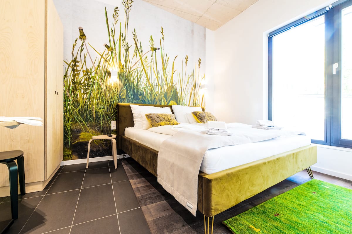 Quarto moderno com uma cama, uma cadeira, um tapete verde e um mural na parede.
