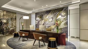 Uma área de recepção moderna com um balcão central, duas cadeiras e um painel decorativo.