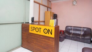 Uma mesa de recepção com uma placa que diz "SPOT ON" e um sofá de couro marrom ao fundo.