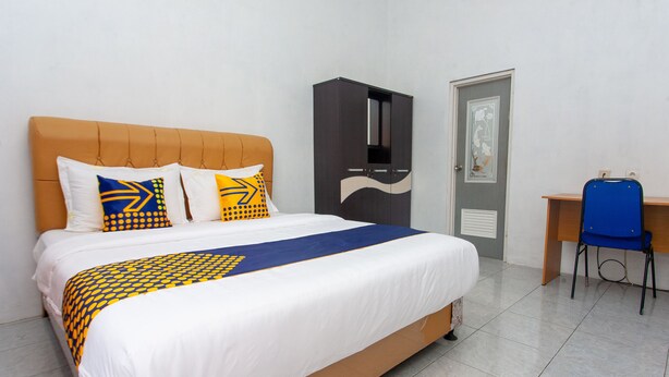 Quarto de hotel com cama, guarda-roupa, secretária e cadeira.