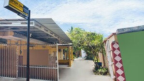 Uma passagem que leva a um edifício com portão de metal e placa amarela.