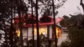 Um edifício com telhado vermelho, rodeado de árvores.
