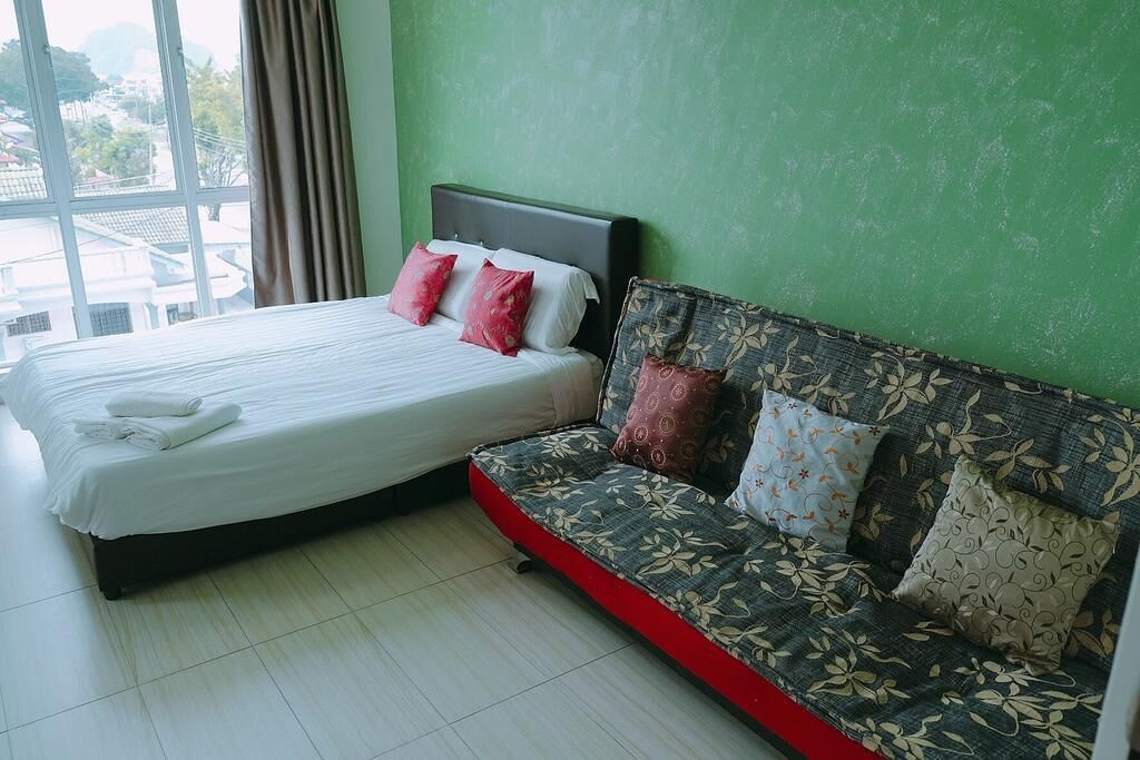 Quarto de hotel com cama, sofá e janela com cortinas.