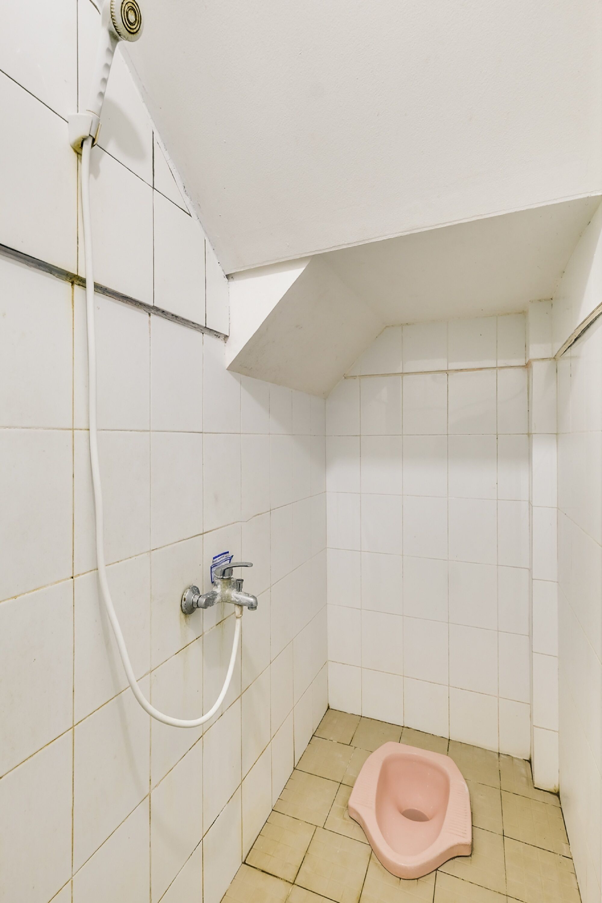 Um banheiro pequeno com azulejos, vaso sanitário, chuveiro e teto branco.