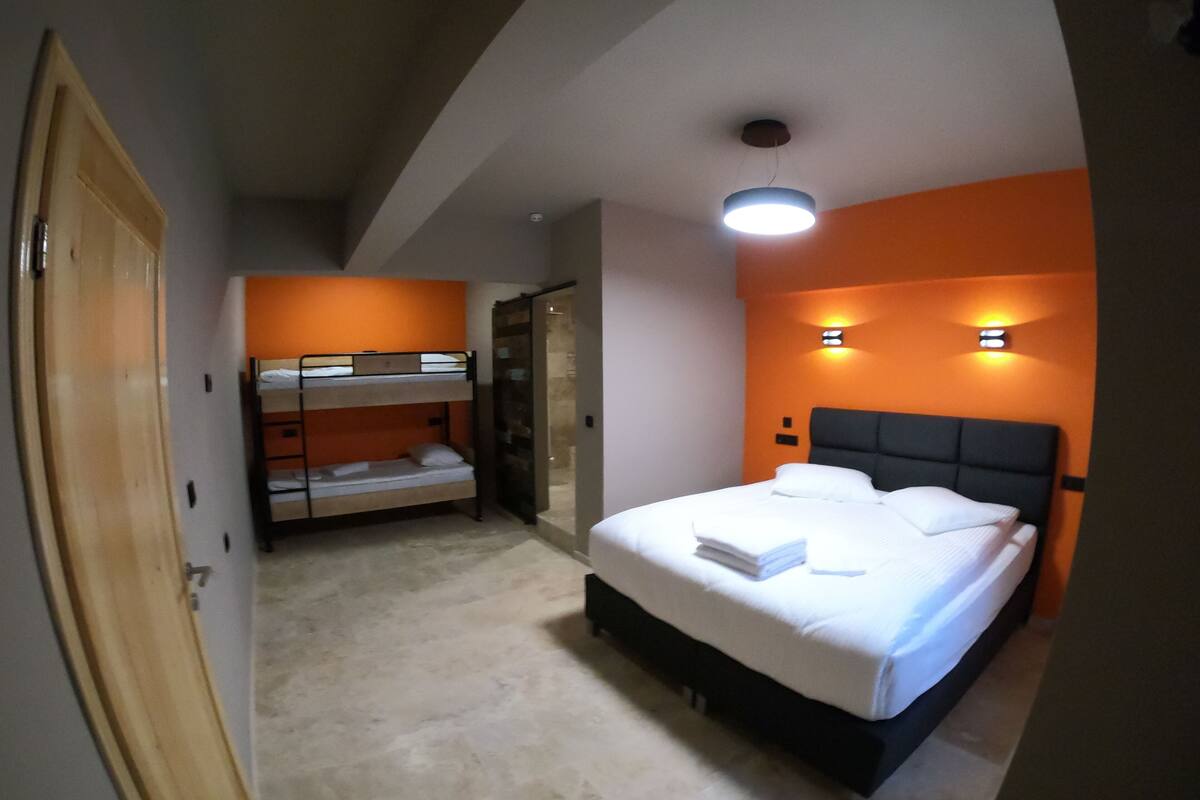 Quarto com cama de solteiro, beliche e luminária no teto.