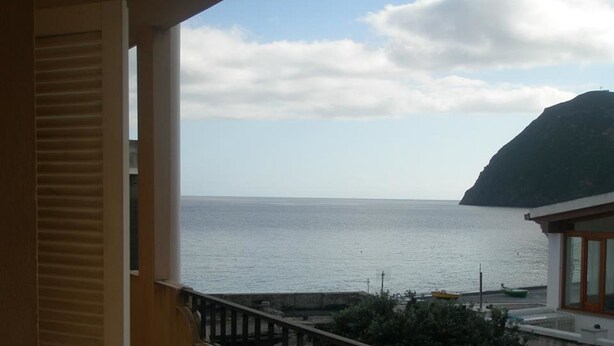 Uma varanda com vista para o mar e uma montanha ao longe.