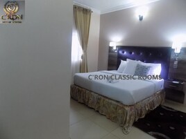Quarto de hotel com cama, cortinas, mesa de cabeceira e abajur.