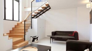 Uma sala de estar moderna com escada, um sofá de couro preto e uma mesa de centro de madeira.