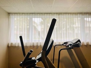 Quarto com equipamentos de ginástica e janela com cortinas leves.