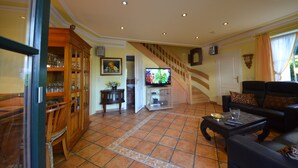 Uma sala de estar com escada, televisão e um espaço de jantar com um armário.