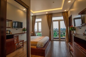 Quarto de hotel moderno com uma cama grande, televisão, escrivaninha e varanda com vista.