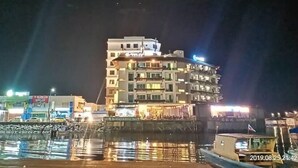 Hotel com vários andares e varandas, situado perto da orla marítima.