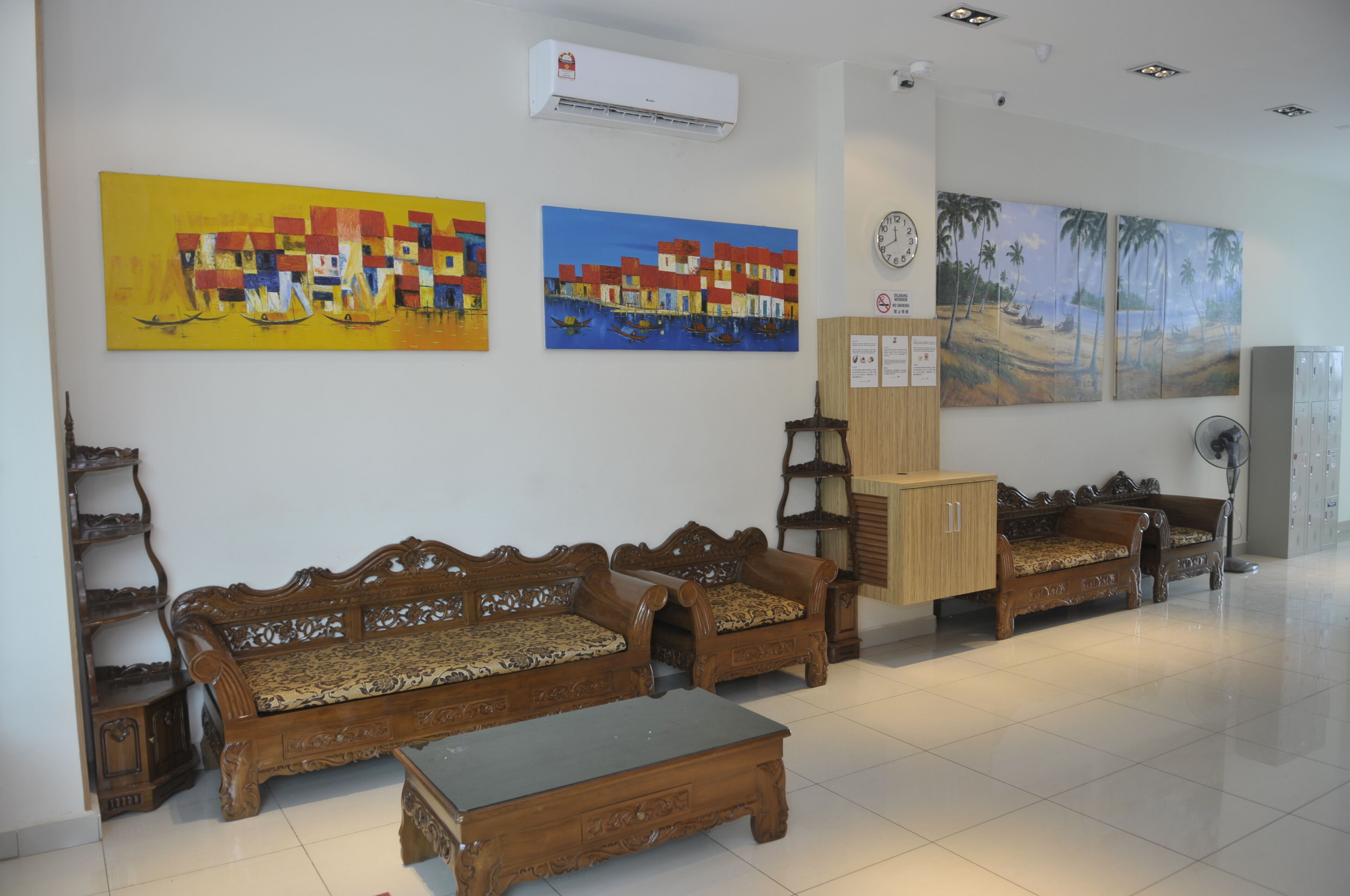 Uma área de recepção com sofás e um armário de madeira, e obras de arte nas paredes.