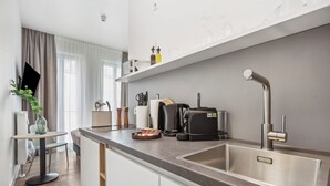 Uma cozinha moderna com uma pia de aço inoxidável, uma cafeteira e um pequeno espaço de jantar com mesa e cadeiras.