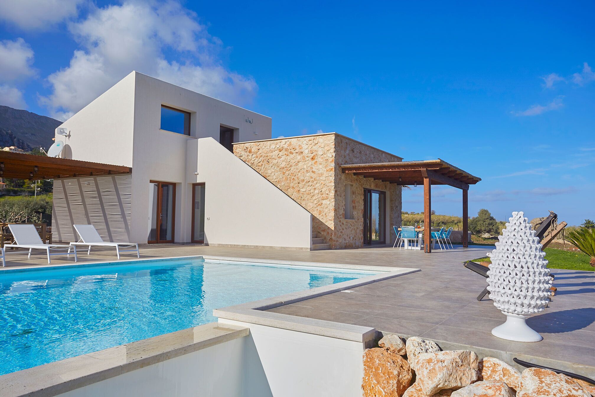 Uma casa moderna com piscina, área de estar externa e fachada de pedra.