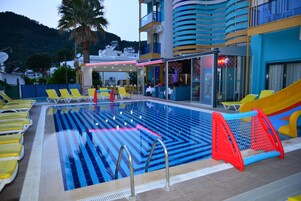 Piscina com espreguiçadeiras amarelas e área de recreação infantil.