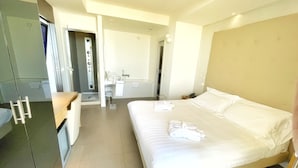 Quarto de hotel moderno com uma cama grande, um banheiro com banheira e uma escrivaninha com cadeira.