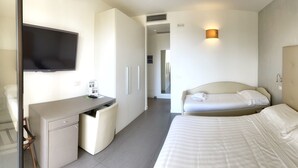 Quarto de hotel com cama, secretária, televisão e banheiro.