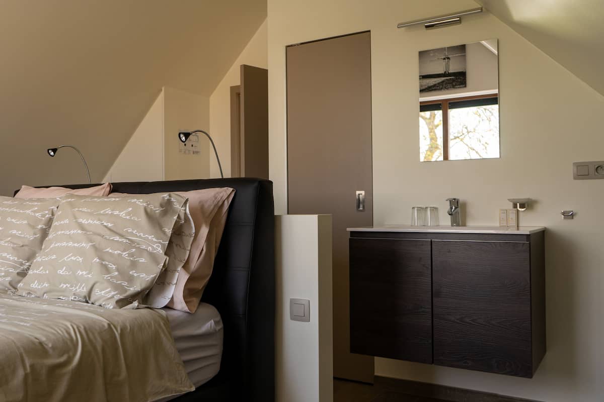 Quarto com cama, abajures, um armário de madeira escura e uma janela.