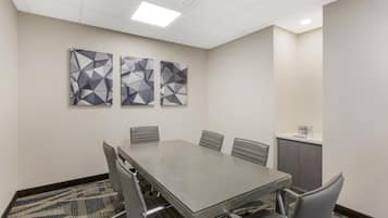 Uma sala de conferências com uma mesa comprida, seis cadeiras e três obras de arte abstratas nas paredes.