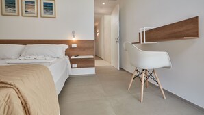Quarto de hotel moderno com uma cama, uma escrivaninha e uma cadeira. Há três quadros na parede.