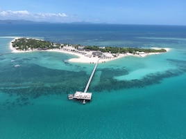 Vista aérea de uma ilha tropical com um cais longo que se estende até o continente.