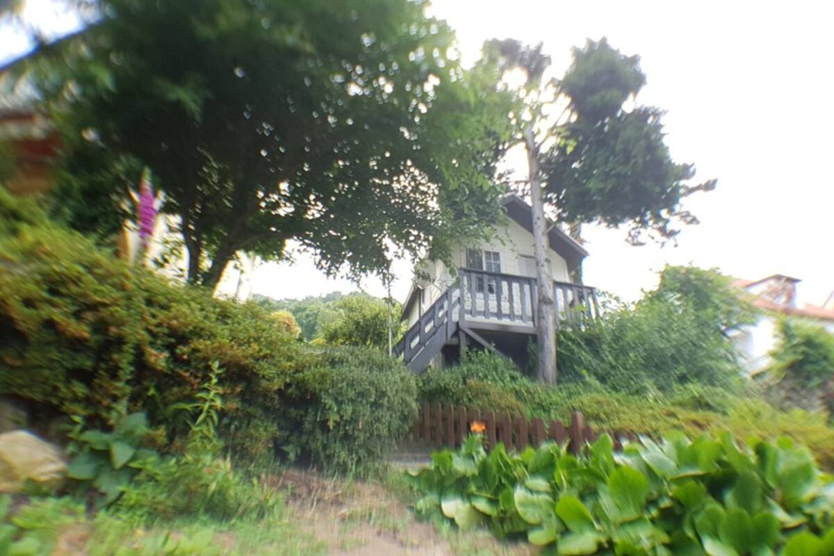 Uma casa com deck de madeira e escada que leva a um segundo andar.
