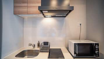 Uma cozinha moderna com pia de aço inoxidável, fogão por indução embutido, micro-ondas e coifa.