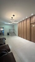 Um hall de hotel moderno com escadas, uma área de recepção e um espaço de estar com cadeiras.