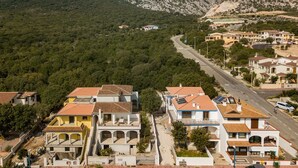 Uma vila costeira com casas em terraços, uma estrada sinuosa e montanhas ao fundo.