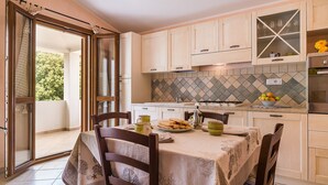 Uma cozinha com armários de madeira, painel de azulejos e uma mesa de jantar posta para dois.