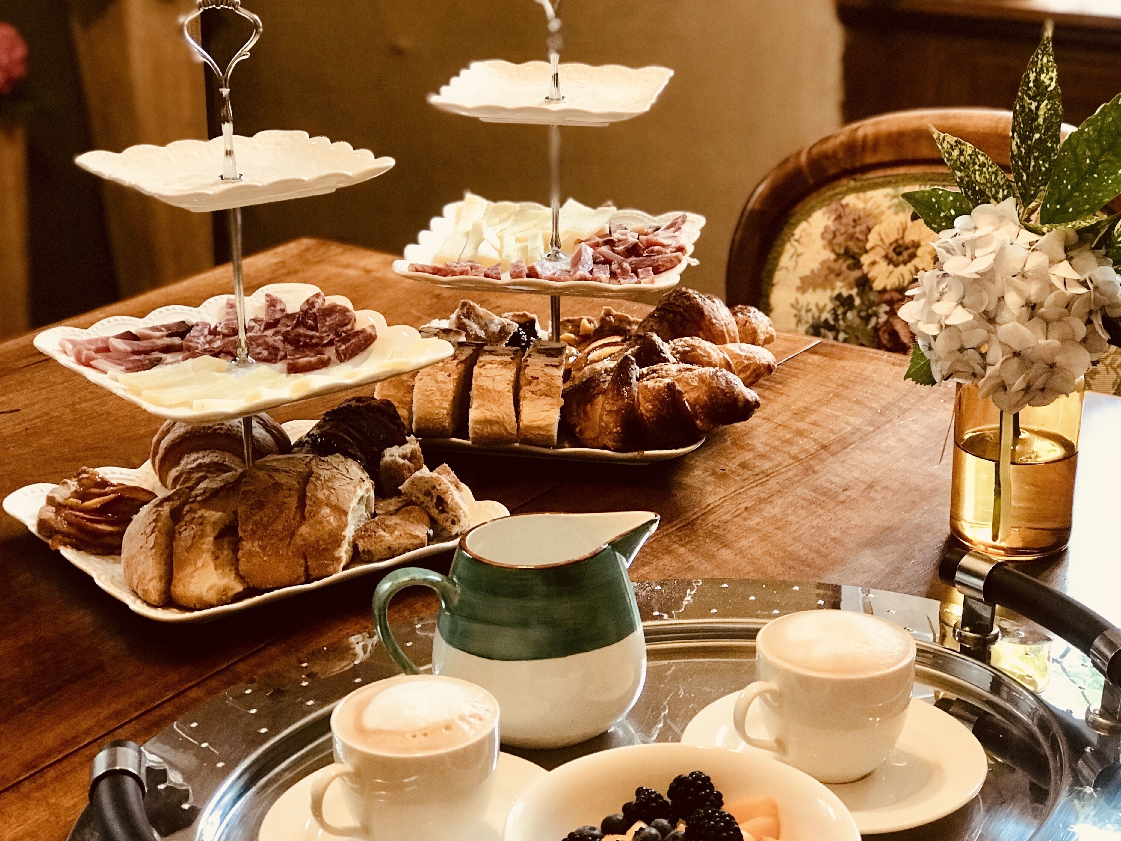 Uma bandeja com doces, um jarro e xícaras sobre uma mesa de madeira.