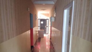 Um corredor com chão de mármore, paredes de madeira e uma porta no final.