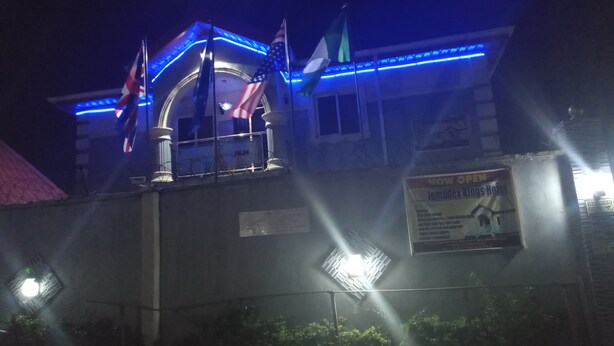 Um edifício com entrada imponente, bandeiras e uma placa indicando ser um hotel.