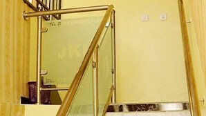 Uma escadaria com guarda-corpo de vidro e um quadro fixado na parede.