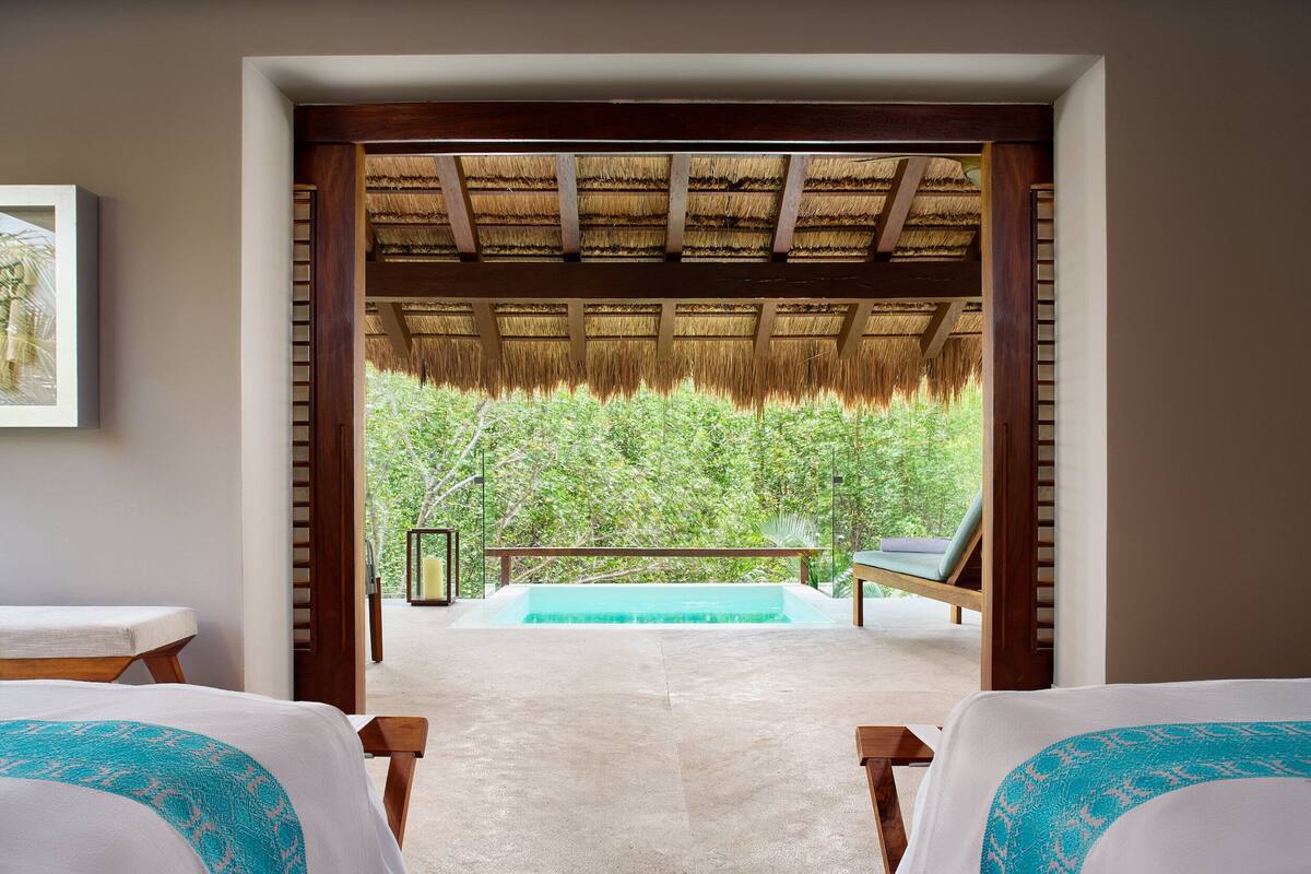 Quarto com cama, uma mesinha e vista para uma piscina ao ar livre.