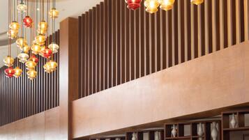 Uma área de recepção moderna com um balcão central, uma luminária decorativa e um painel de parede estampado.