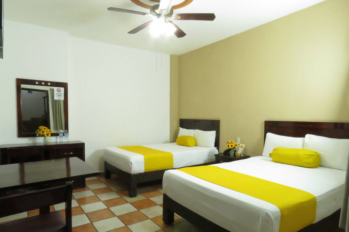 Quarto de hotel com duas camas, uma escrivaninha e uma cadeira.