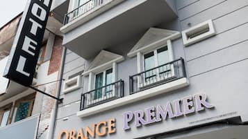 Um hotel chamado 'Orange Premier' com uma varanda e um painel digital.