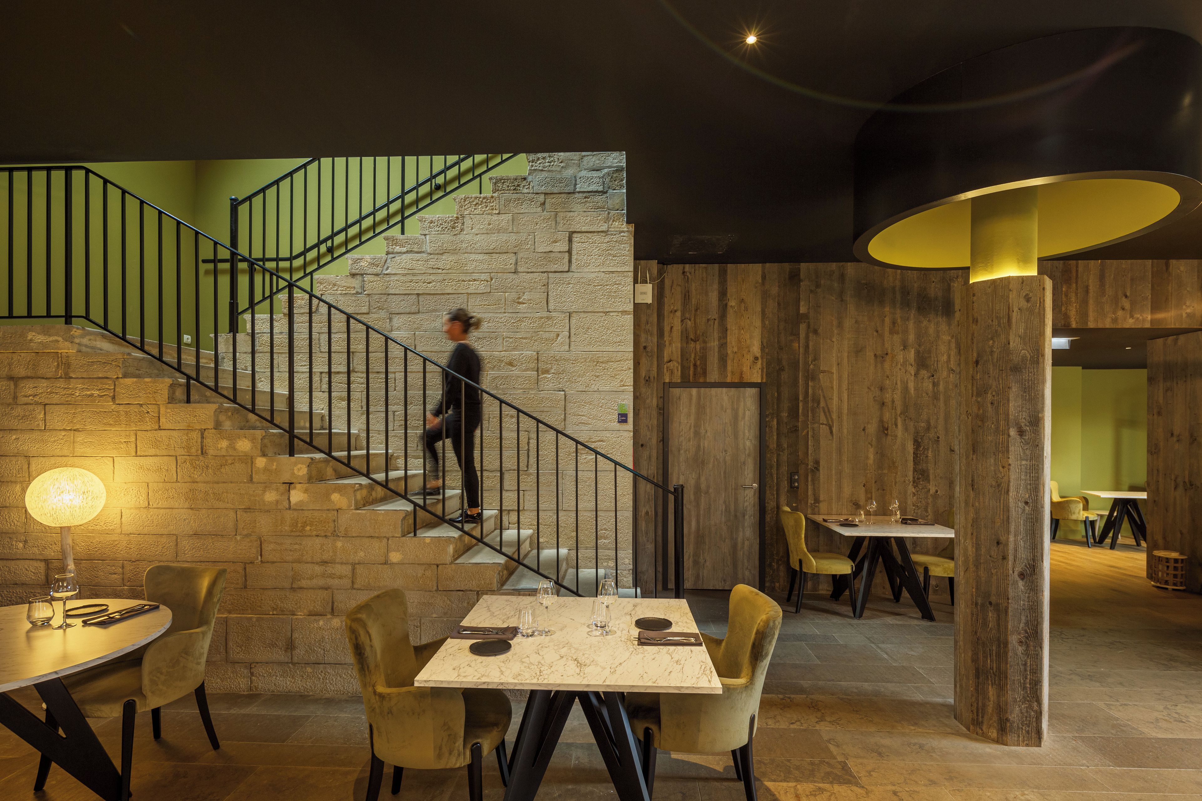 Restaurante com escadaria de pedra, paredes de madeira e área de refeições com mesas e cadeiras.