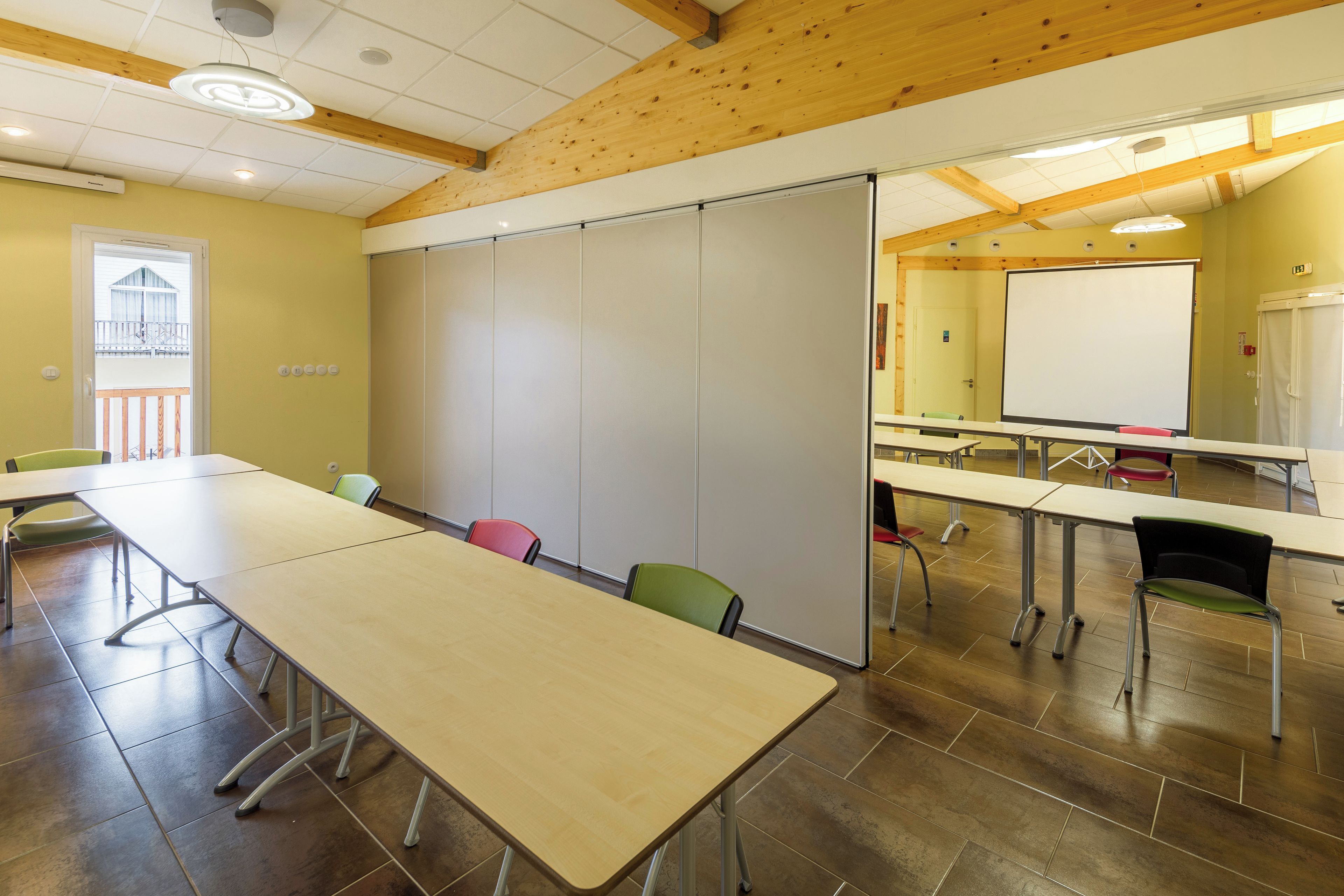 Uma sala de conferências com uma mesa comprida, cadeiras, um quadro branco e uma tela de projetor.
