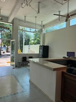 Uma área de recepção com balcão, cadeiras, computador e vista para o exterior.