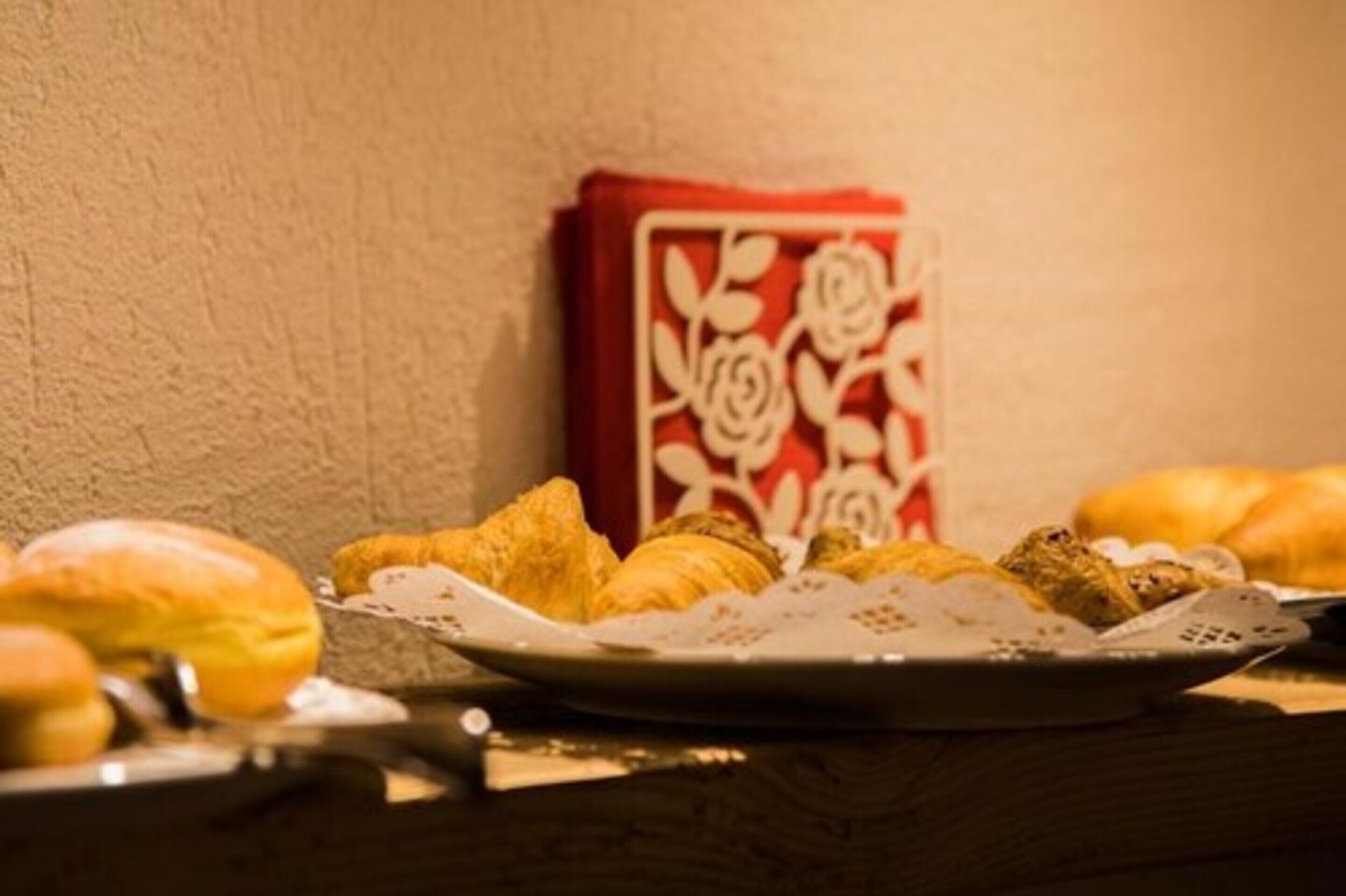 Um prato de croissants sobre uma mesa, com uma toalha decorativa ao fundo.