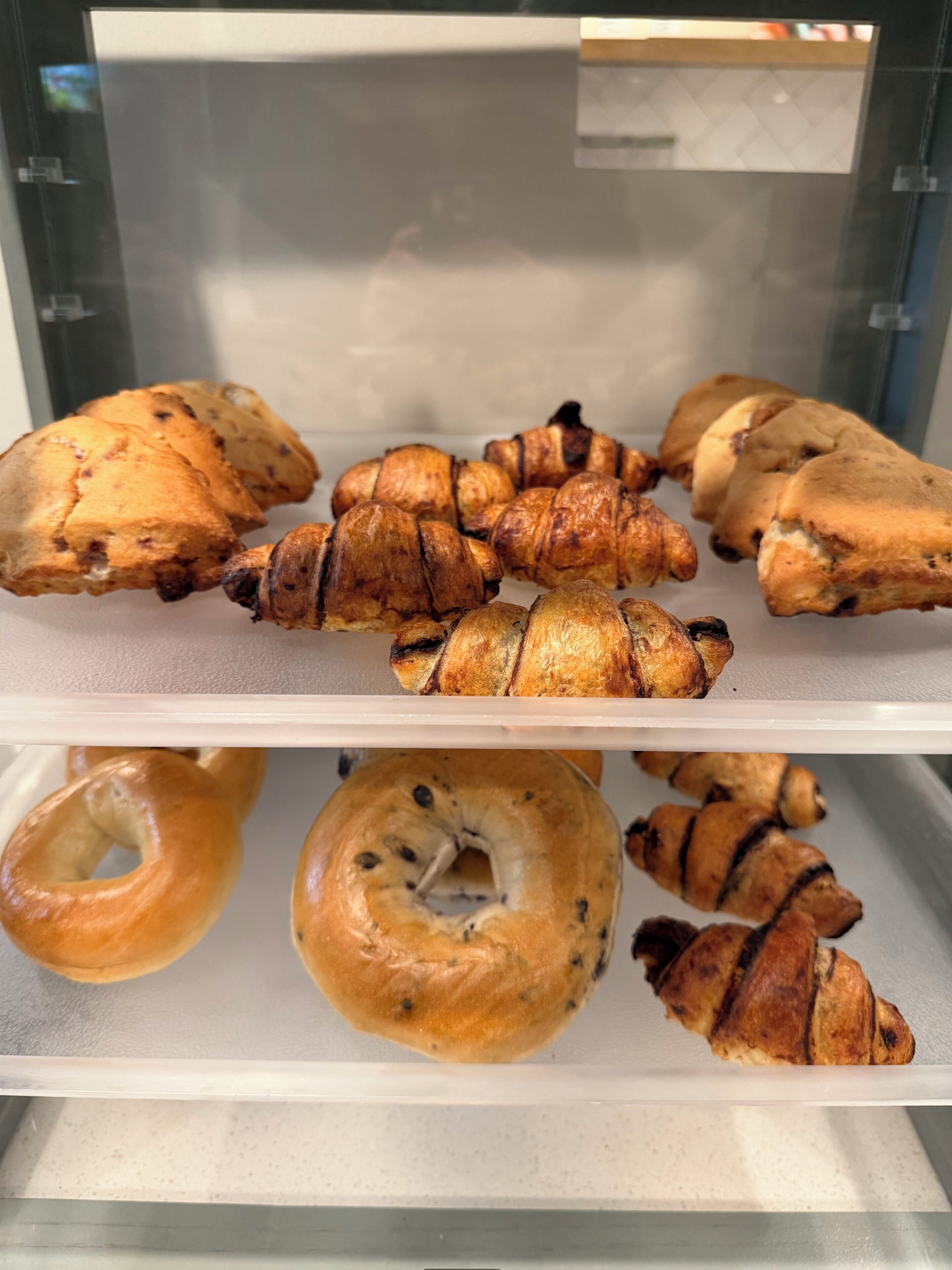 Vitrine de pastelaria com croissants e bagels.