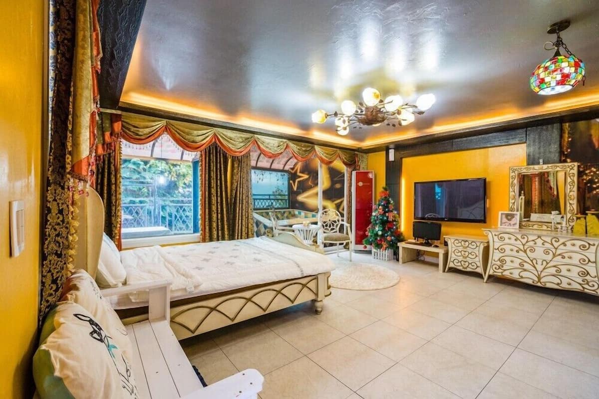 Quarto com cama, televisão, penteadeira e árvore de Natal.