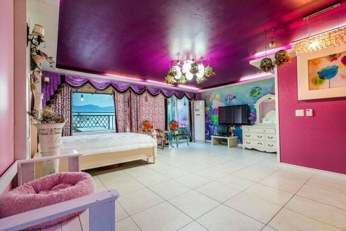 Quarto com cama, penteadeira, televisão e janela com vista.