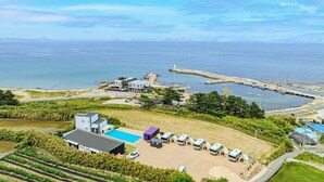 Um imóvel costeiro com piscina, estacionamento para trailers e um cais que se estende para o mar.